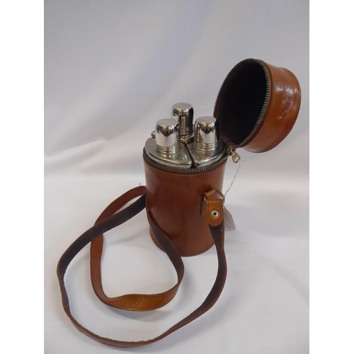 Set of 3 chrome top glass hip flasks in cylindrical leather case with strap