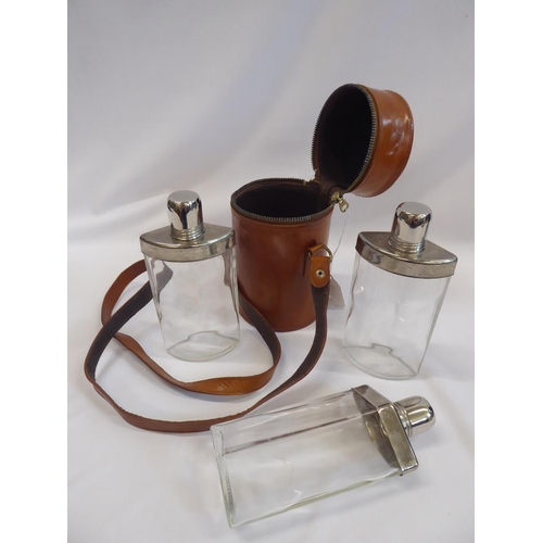 Set of 3 chrome top glass hip flasks in cylindrical leather case with strap