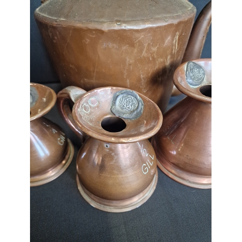 A selection of quarter, half and and one gill copper measuring jugs and ...