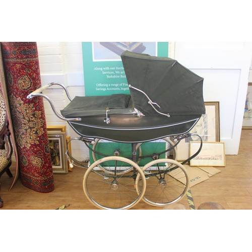 A silver cross green coach-built pram on two pairs of spoked wheels ...