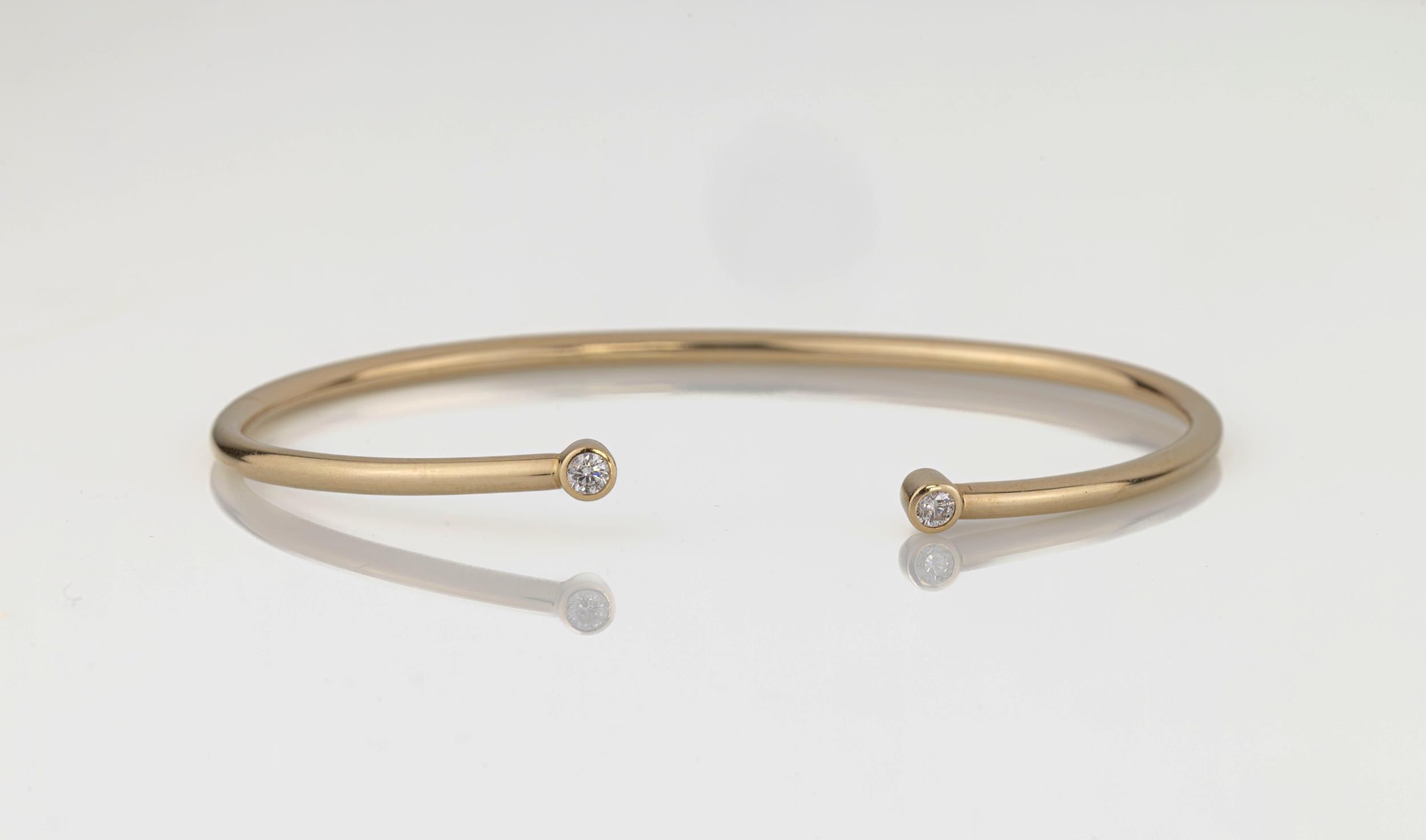 An 18ct yellow gold and diamond flexible torc style bangle, the plain ...