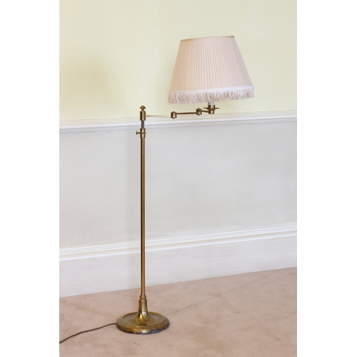 An adjustable brass reading lampwith dished circular base, hinged arm ...