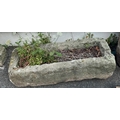 A weathered rounded rectangular granite trough. approximately 24cm high by 95cm in length and 40cm w