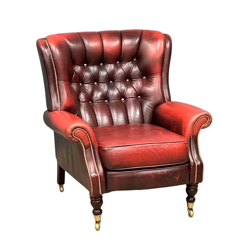 A Victorian style deep buttoned ox blood leather armchair on brass cup ...