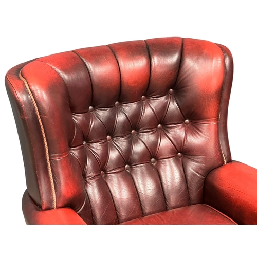 A Victorian style deep buttoned ox blood leather armchair on brass cup ...