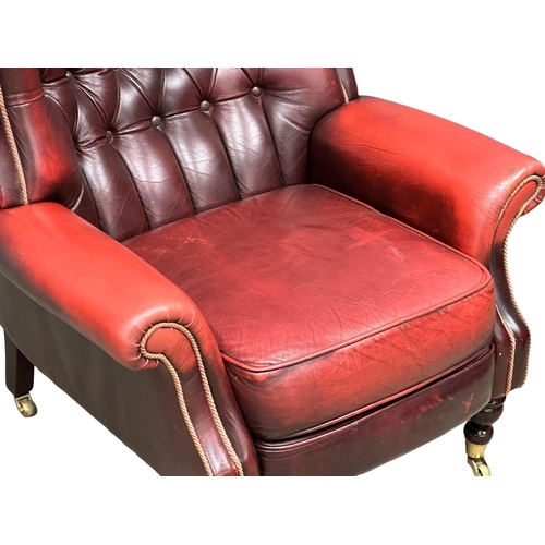 A Victorian style deep buttoned ox blood leather armchair on brass cup ...