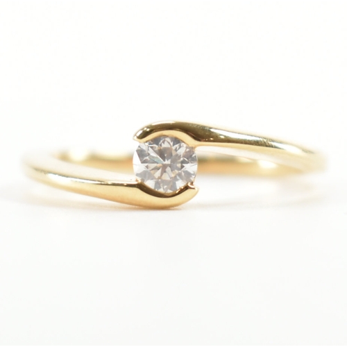A yellow gold & diamond crossover solitaire ring. The single stone ...
